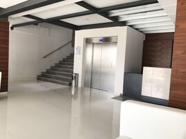 Um hall moderno com escada, elevador e piso lustroso.