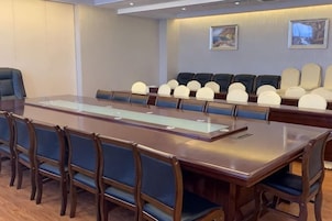 Uma sala de conferências com uma mesa comprida, cadeiras e um quadro branco.