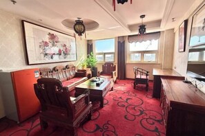 Quarto tradicional com tapete vermelho, mobiliário de madeira, uma grande obra de arte emoldurada e vista pela janela.