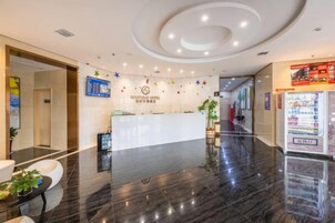 Uma área de recepção de hotel com piso de mármore, balcão de atendimento e máquina de vendas automática.
