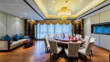 Quarto espaçoso com mesa de jantar, cadeiras, sofá e televisão.