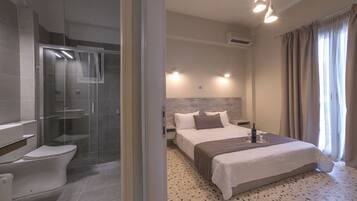Quarto de hotel moderno com chuveiro, vaso sanitário e cama.