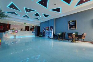 Um saguão de hotel com balcão de recepção, área de estar e totens digitais.