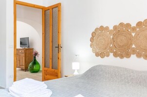 Um quarto com uma cama, uma porta de madeira, uma televisão, um armário e um objeto decorativo na parede.