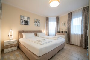 Quarto de hotel com uma cama grande, mesas de cabeceira, um espelho e obras de arte nas paredes.