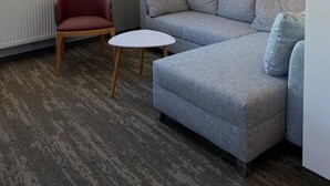 Uma sala de estar moderna com um sofá cinzento, uma poltrona vermelha e uma pequena mesa branca.