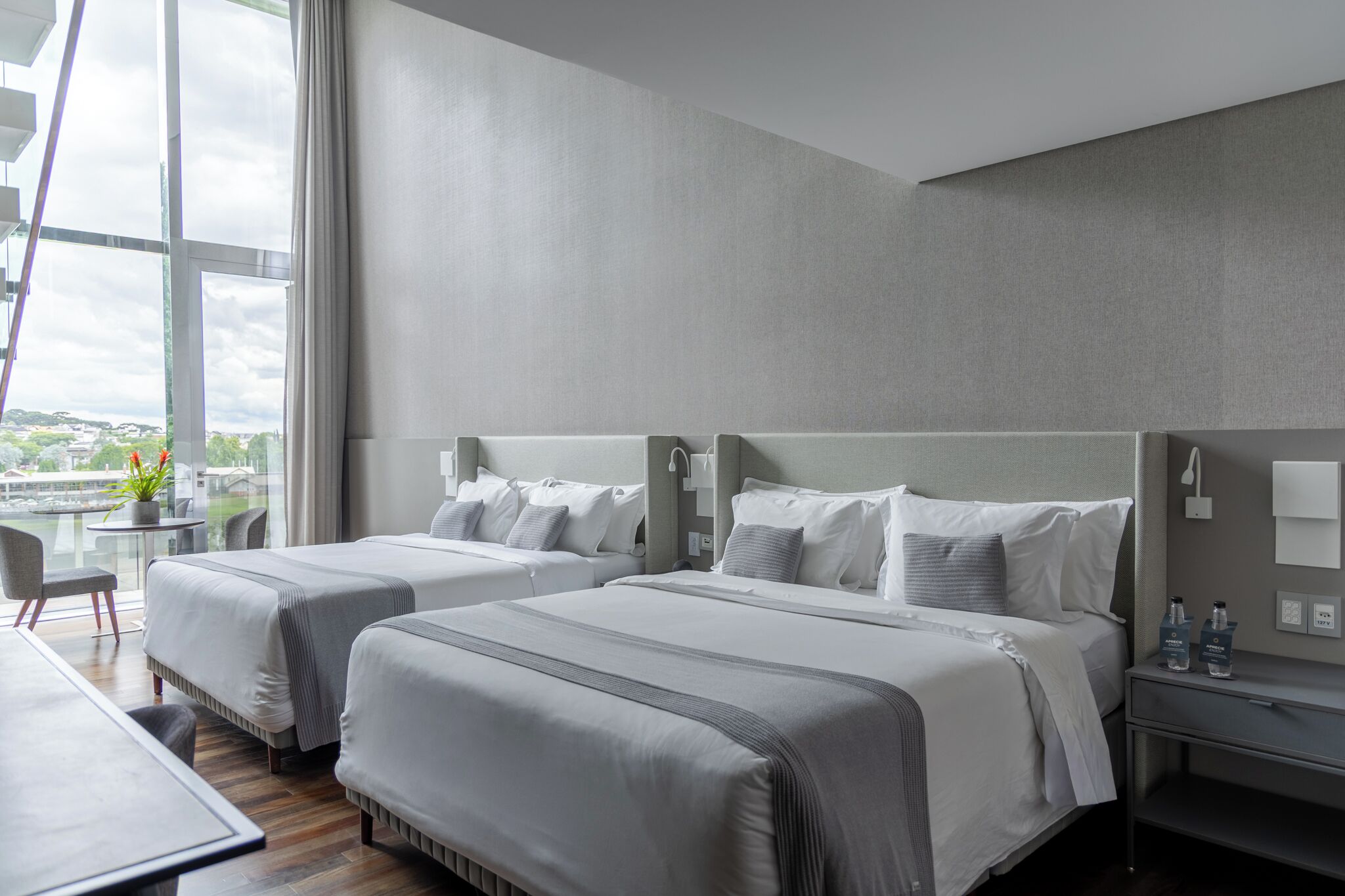 Quarto de hotel com duas camas, uma escrivaninha e vista para a paisagem urbana.