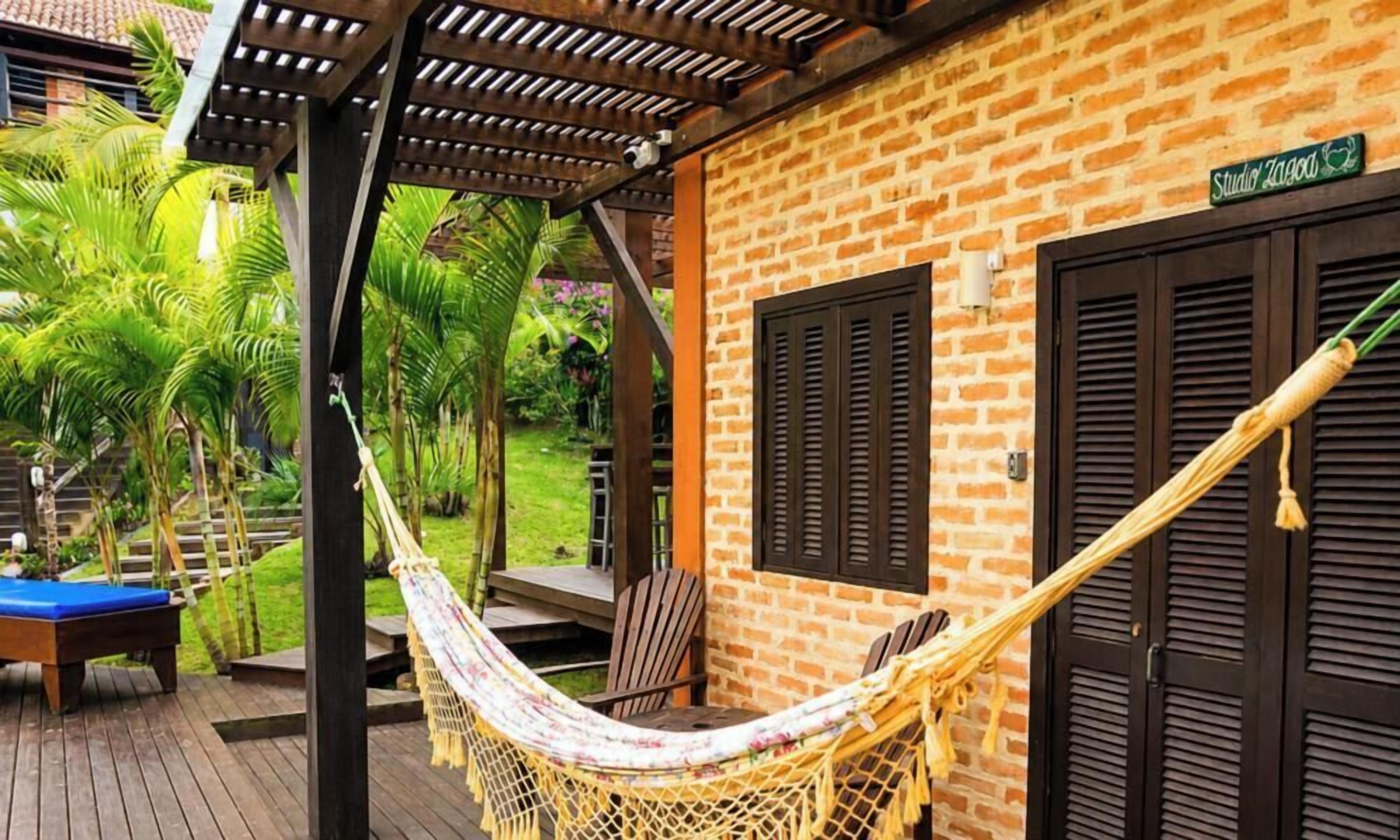 Um edifício de tijolos com uma rede, área de estar ao ar livre e piscina.