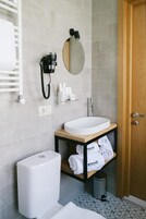 Uma casa de banho moderna com lavatório branco, espelho, secador de cabelo e sanita.