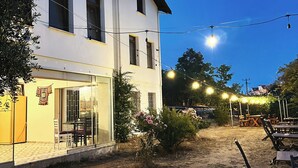 Um edifício de dois andares com restaurante no térreo e área externa para sentar.