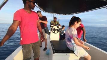 Um barco com timão, passageiros e um toldo.