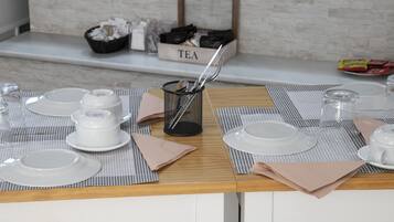 Uma mesa de jantar bem arrumada com pratos e tigelas brancos, e uma caixa de chá com a etiqueta