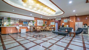 Um saguão de hotel com balcão de recepção, área de estar e um grande lustre.