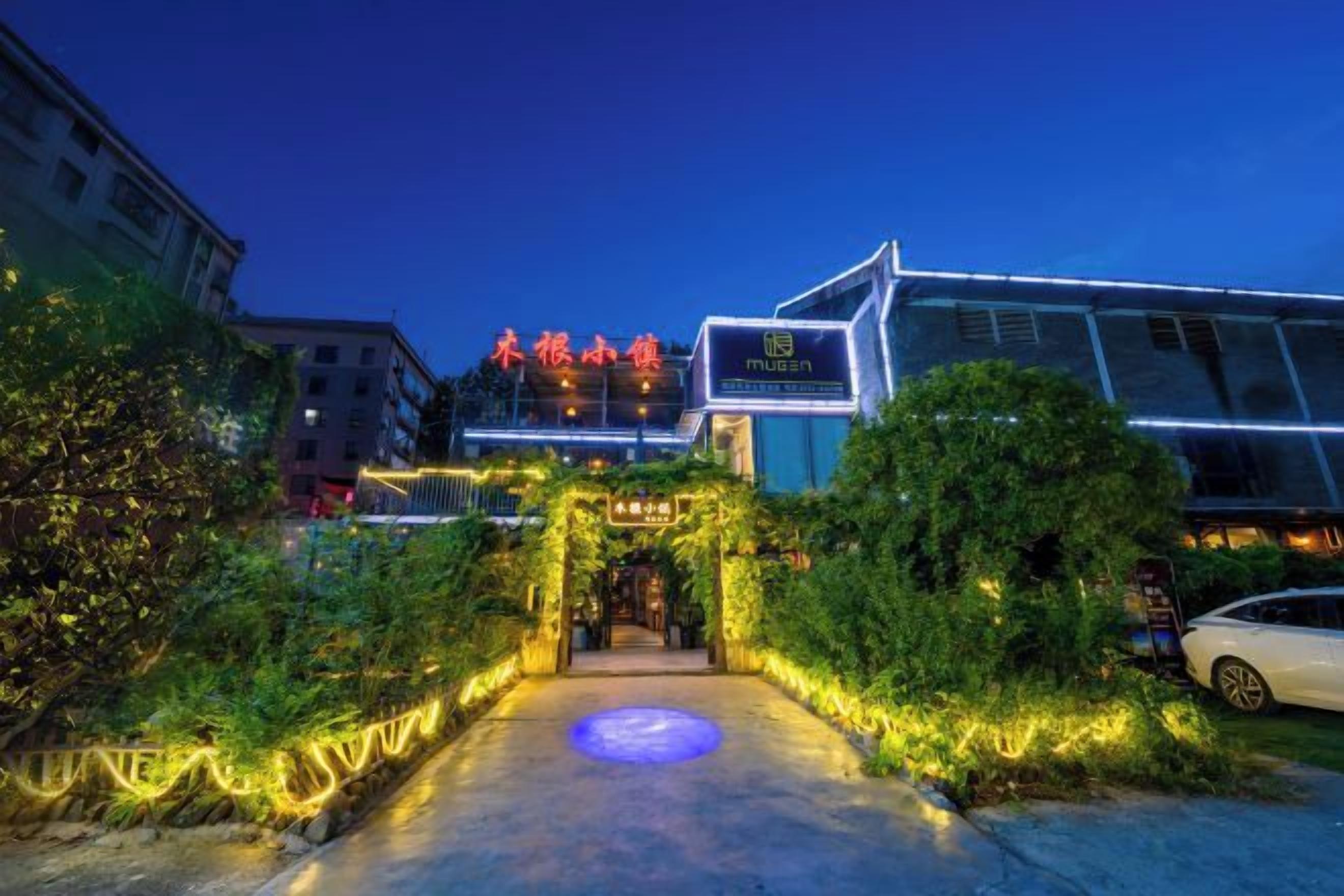 Entrada de hotel com um caminho que leva ao edifício principal, cercada por vegetação.