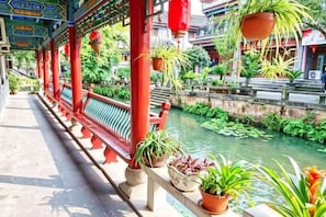Corredor tradicional com telhados vermelhos, bancos e plantas em vasos ao longo de um canal.