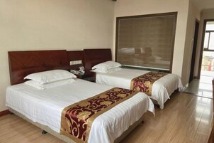 Quarto de hotel com duas camas, uma janela grande e soalho de madeira.