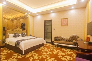 Quarto de hotel com uma cama grande, um sofá, uma mesinha e uma televisão.