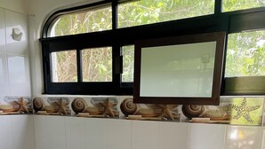 A bathroom with a white sink, a toilet, and a window with a view of greenery.