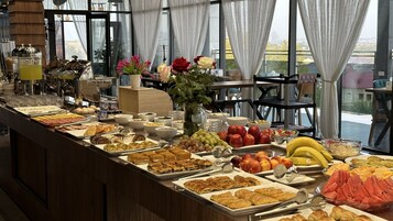 Buffet com diversos alimentos e um vaso de flores.
