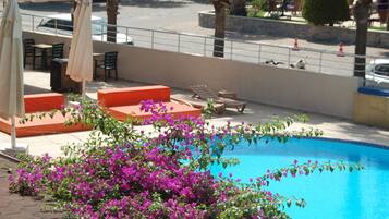 Área de piscina com assentos laranja e um canteiro de flores.