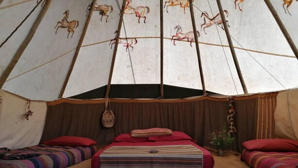 Uma tenda com cama, almofadas e um enfeite pendurado.