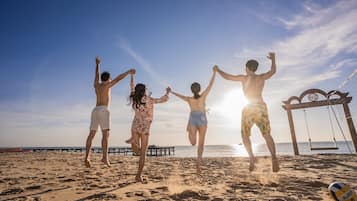 Uma praia com uma rede de voleibol e um cais ao fundo.