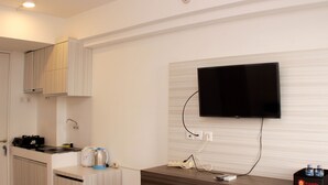 Uma cozinha moderna com fogão embutido, pia e televisão de tela plana presa na parede.