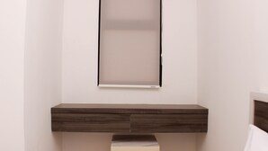 Um banheiro minimalista com toucador de madeira, um espelho e porta-toalhas.