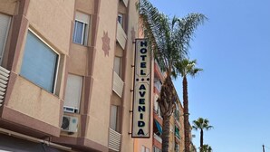 Um hotel com fachada em formato de estrela, várias varandas e uma placa indicando sua localização na Avenida.