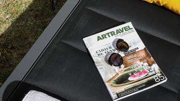 Uma área de estar com uma revista, um copo de bebida e uma almofada amarela.