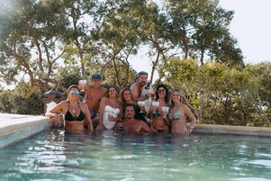 Um grupo de pessoas em uma piscina, com árvores ao fundo.