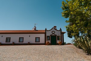 Um edifício com telhado de azulejos, porta verde e vasos de plantas.