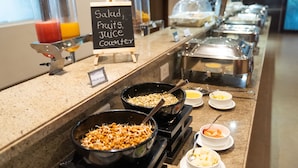 Balcão de buffet com diversas opções de comida, incluindo saladas, frutas e sucos.