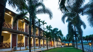 Um hotel com várias varandas, palmeiras e um gramado bem cuidado.
