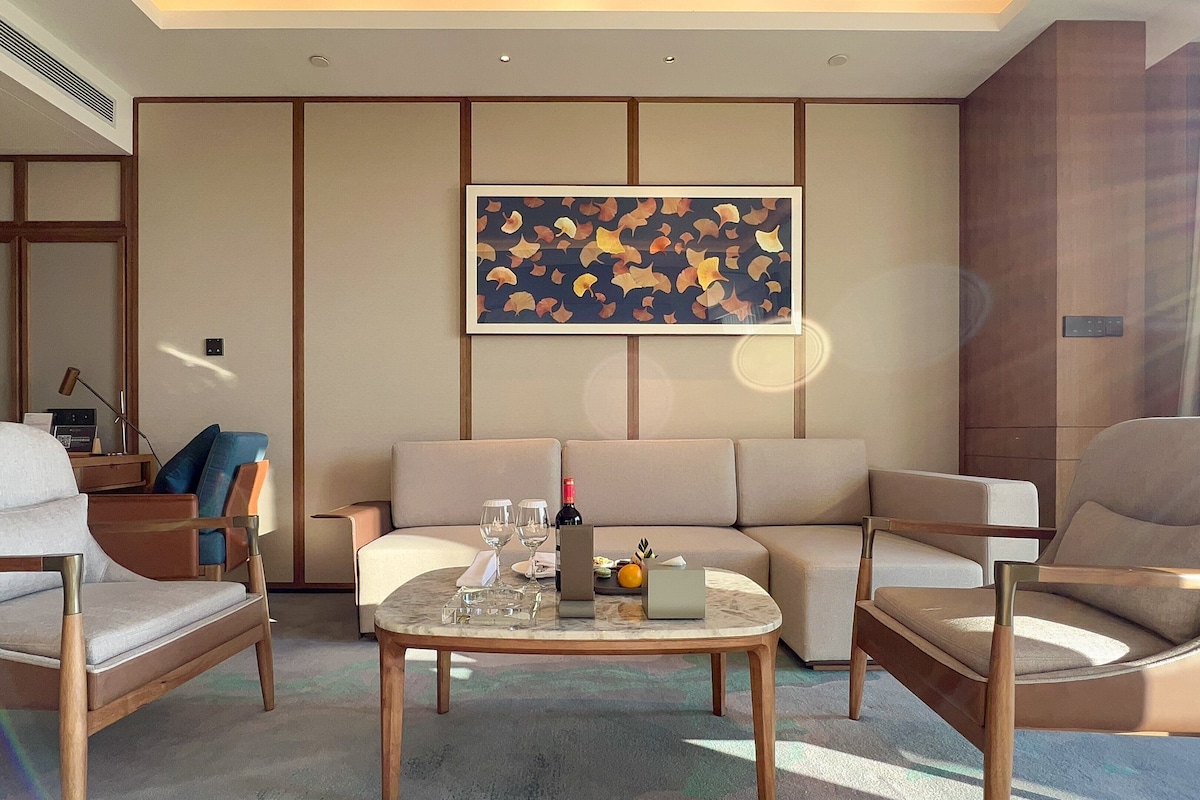 Uma sala de estar moderna com um sofá, duas poltronas, uma mesa de centro e um quadro na parede.