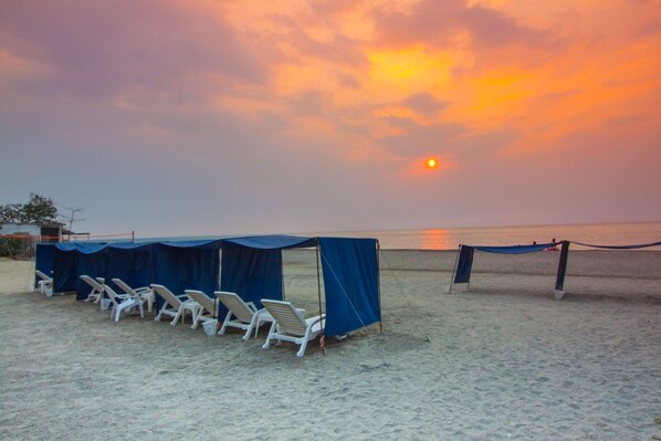 Uma praia com cadeiras de praia e área coberta, provavelmente para banhos de sol ou relaxamento.