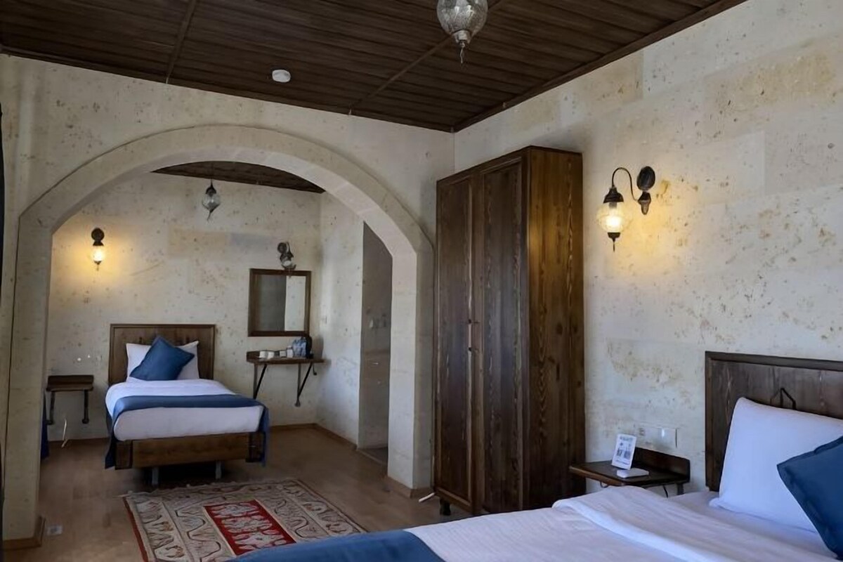 Quarto com cama, guarda-roupa, espelho e duas luminárias.