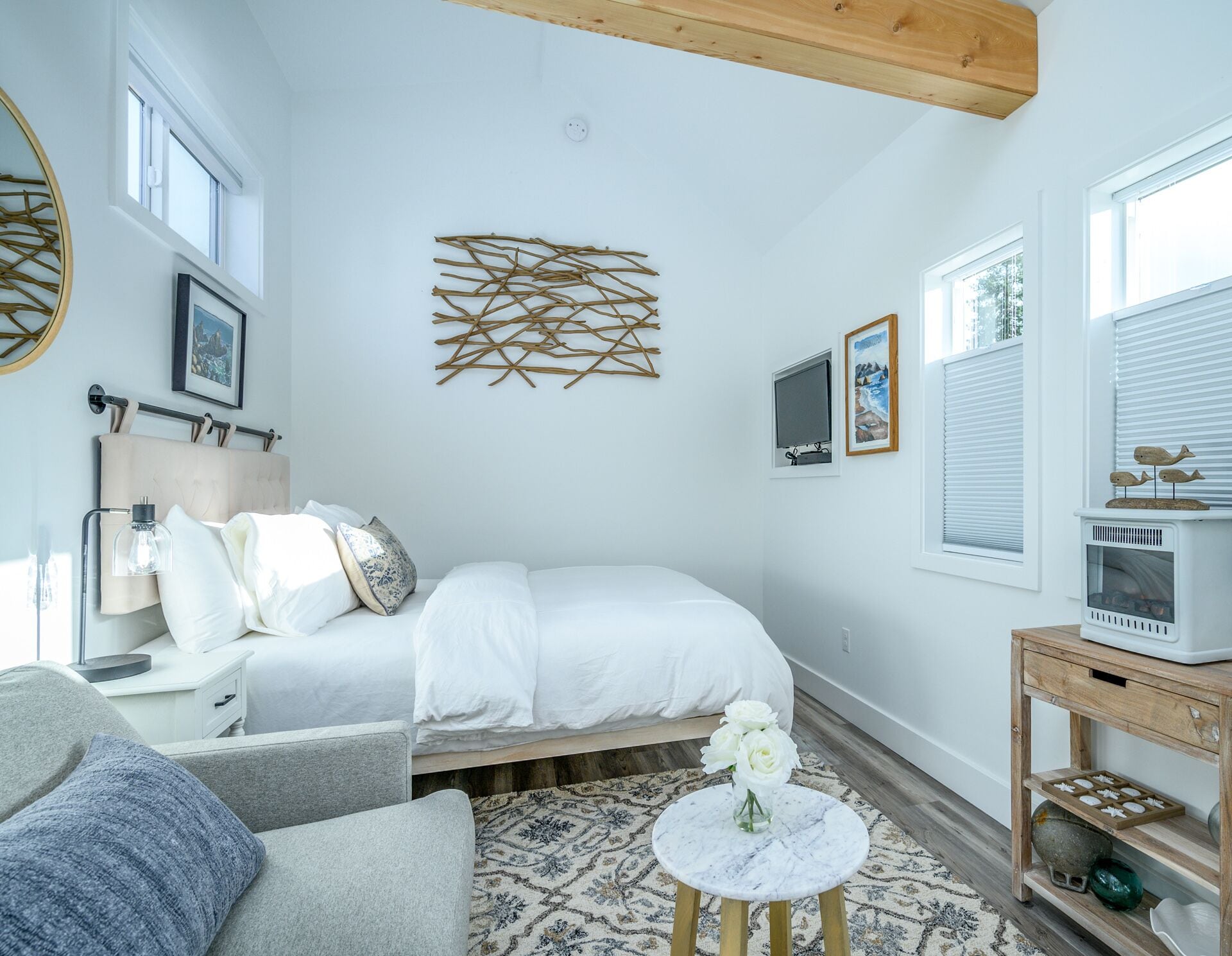 Um quarto moderno com cama, mesa de cabeceira, abajur e uma pequena mesa redonda com flores.