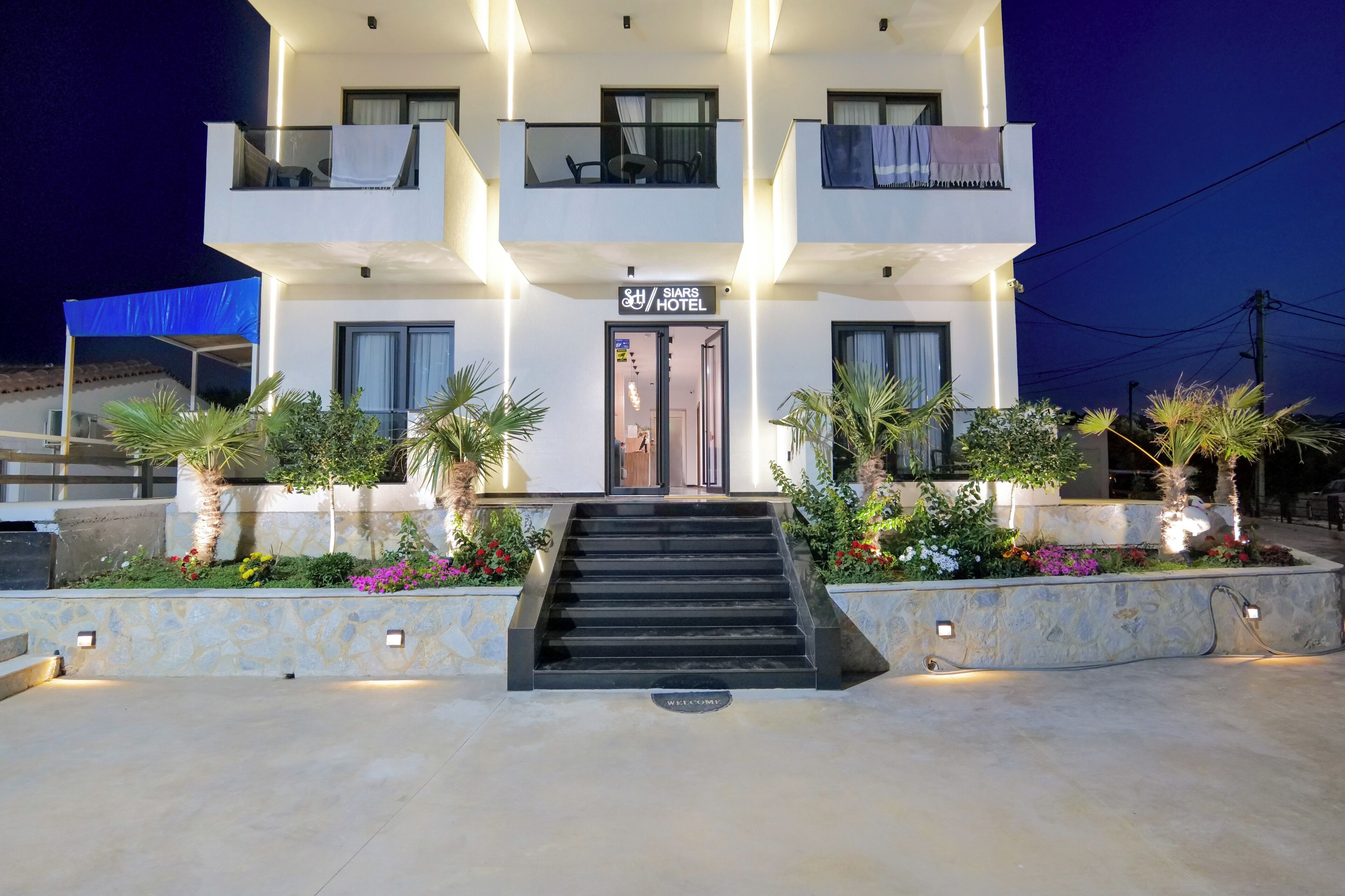 Um hotel moderno com estrutura em dois andares, entrada convidativa com degraus e uma placa.