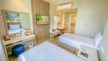 Quarto de hotel com duas camas, uma escrivaninha, uma cadeira, televisão, espelho e ar condicionado.
