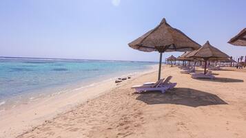 Na praia, espreguiçadeiras, guarda-sóis de praia, toalhas de praia