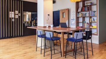 Um espaço de trabalho moderno com uma mesa de madeira, quatro cadeiras azuis, uma estante com livros e uma parede decorativa com cordas verticais.