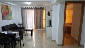Uma sala de jantar com mesa, cadeiras, televisão e sofá.