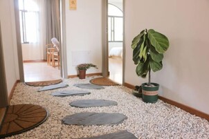 Um caminho com pedras irregulares leva a um quarto com cama e janela.