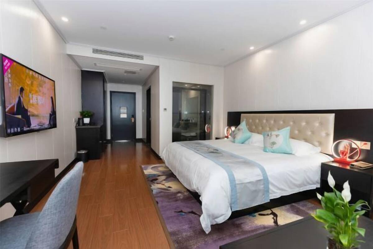 Quarto de hotel moderno com uma cama grande, uma mesa de trabalho e uma televisão.