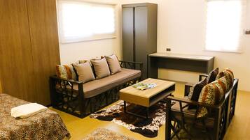 Um quarto com sofá, cadeiras, mesa, armário e cama.