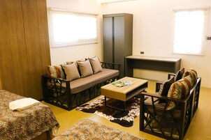Um quarto com sofá, cadeiras, mesa, armário e cama.