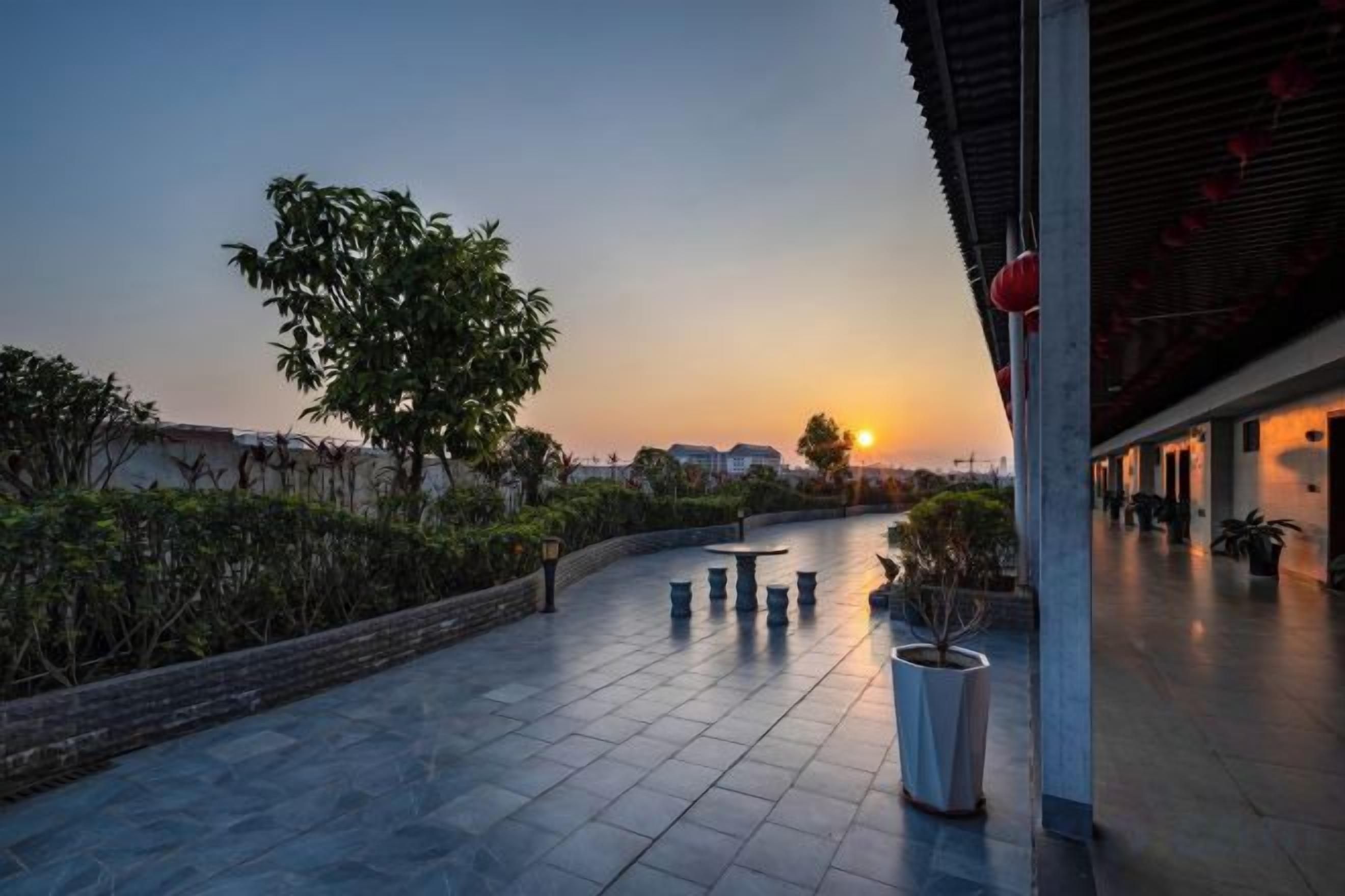 Um terraço ao ar livre com um caminho sinuoso, plantas em vasos e vista para o pôr do sol.