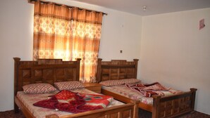 Quarto com duas camas de madeira, cortina estampada e chão de azulejos.