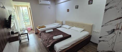 Quarto de hotel com cama, escrivaninha, cadeira, guarda-roupa e ventoinha no teto.